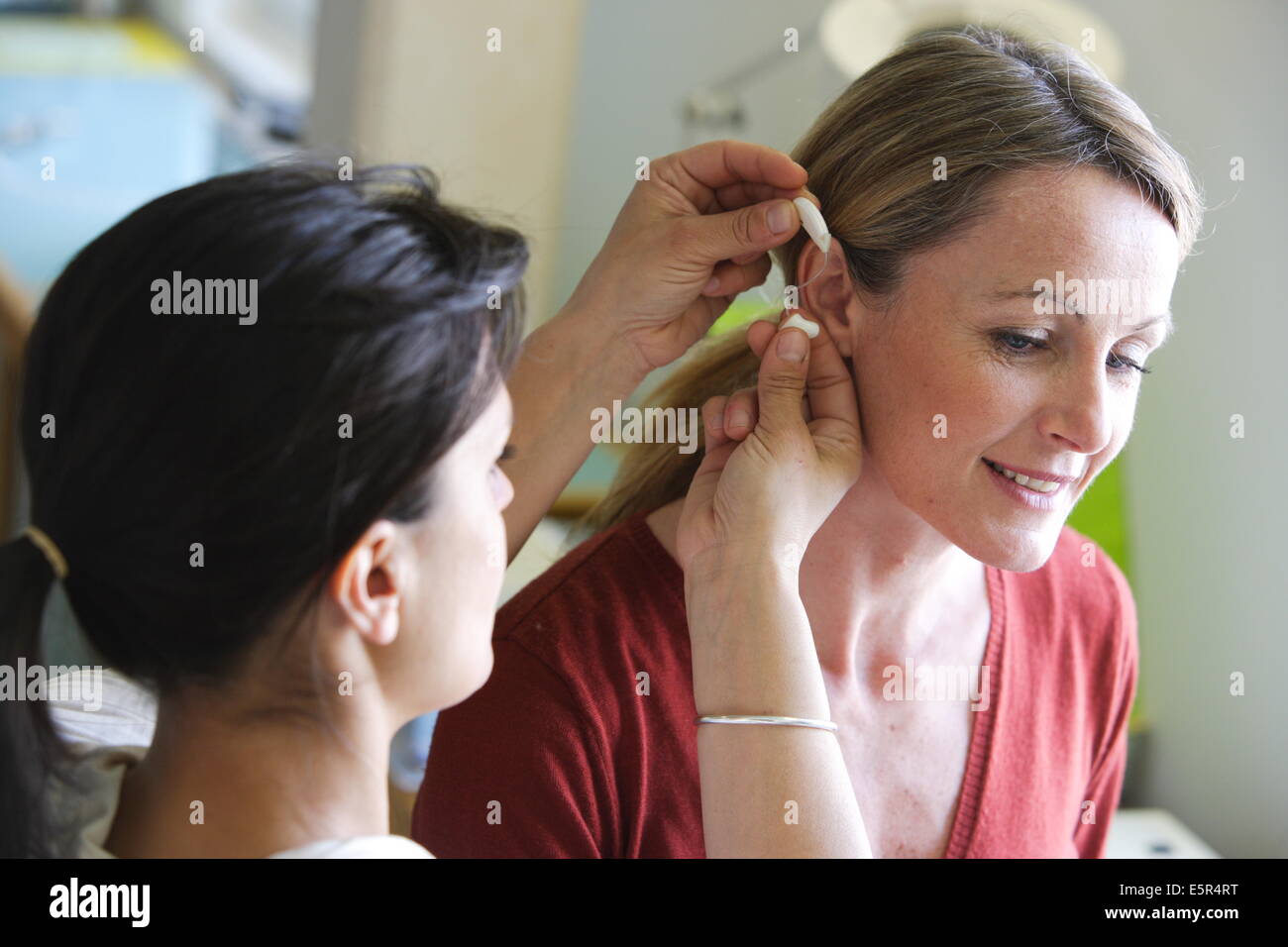 A hearing aid specialist fits a digital hearing aid for a woman Stock ...