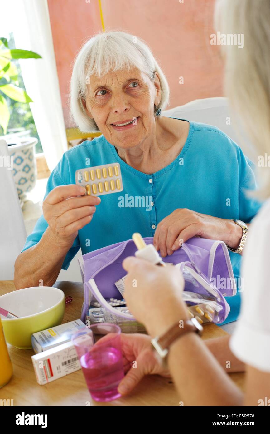 Woman assisting 80 year old woman taking medication Stock Photo - Alamy