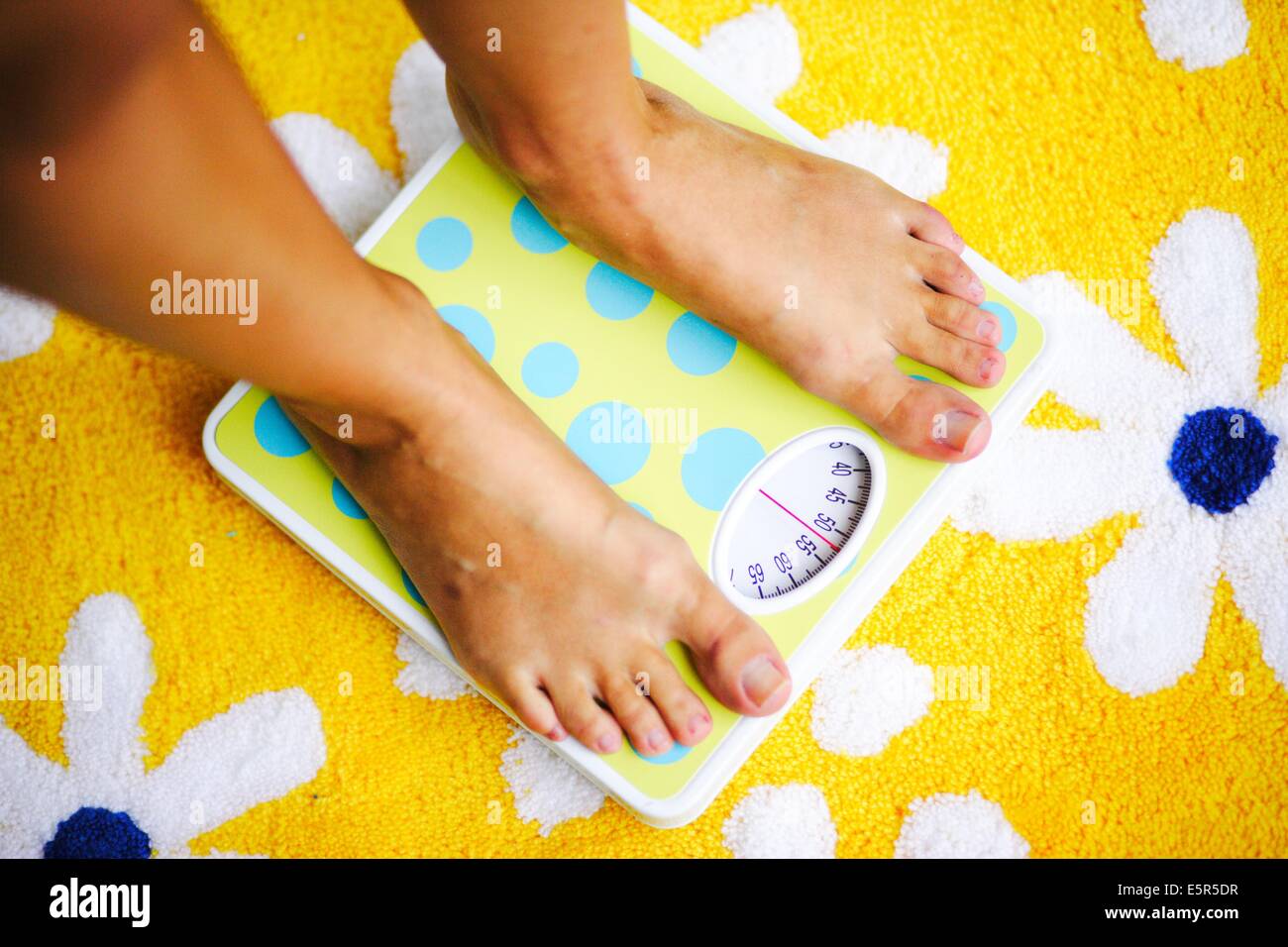 Woman checking her weight on a scale Stock Photo - Alamy