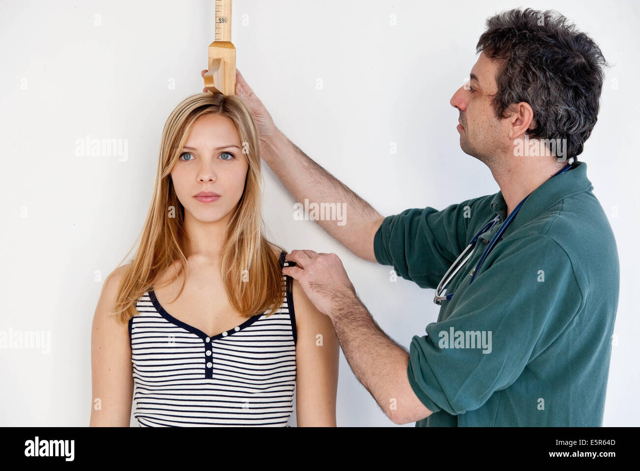 General practitioner measuring the height of a patient during medical ...