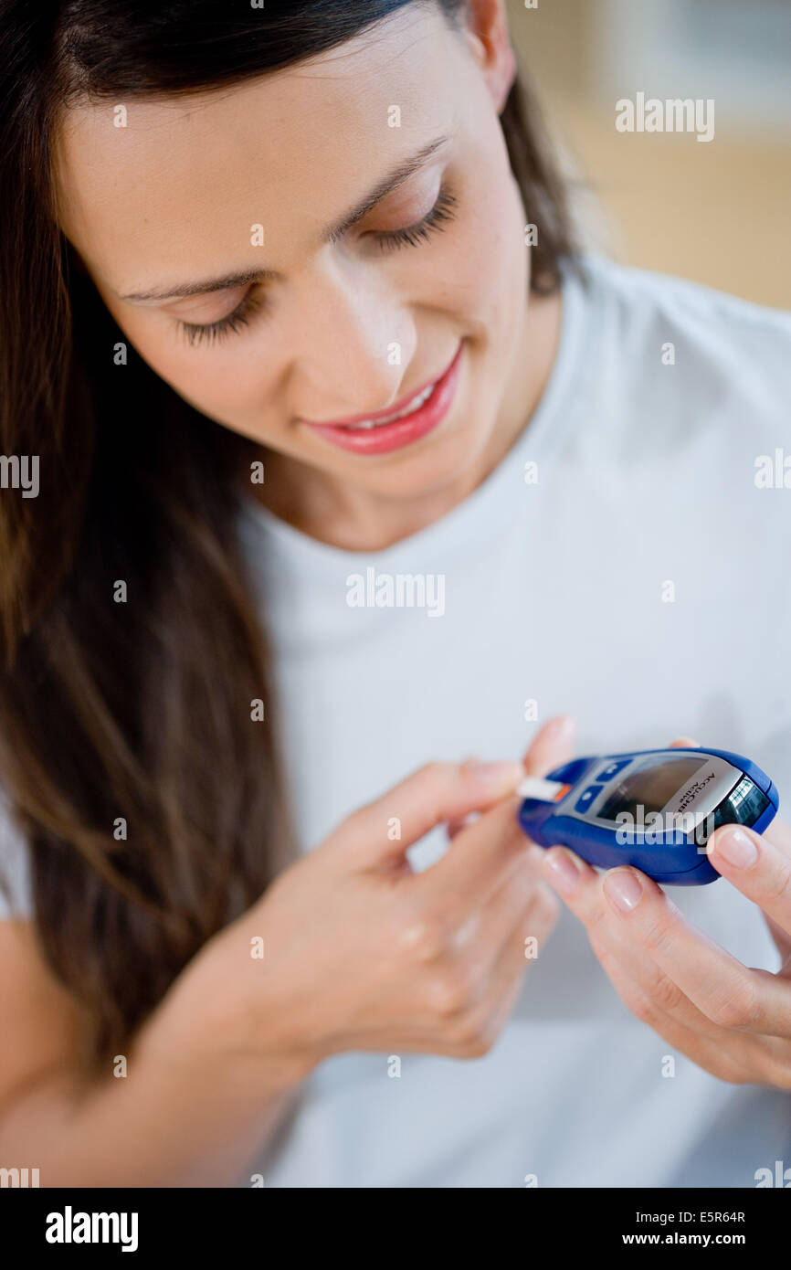 A diabetic person is checking her blood sugar level (self glycemia)with ...