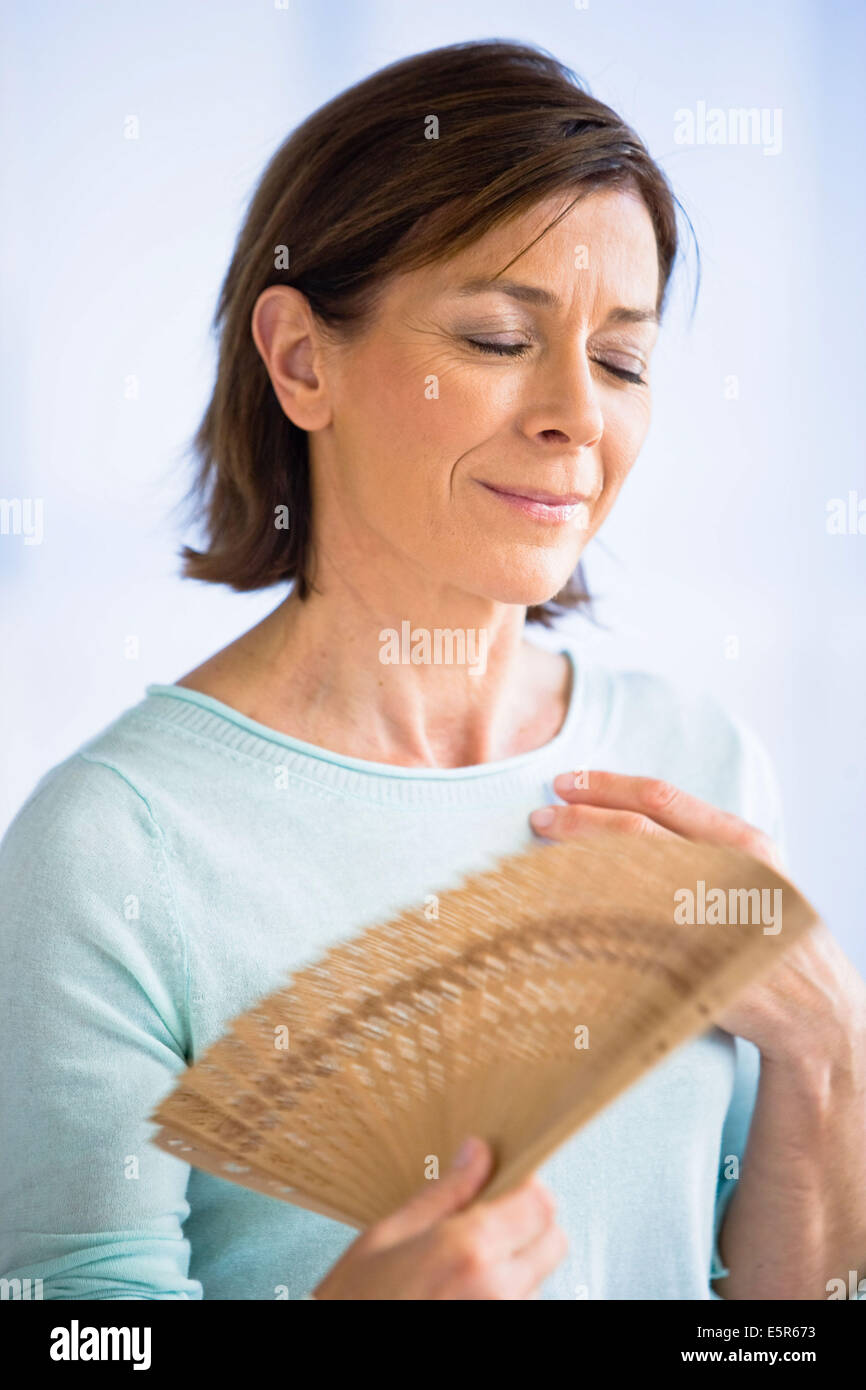 Woman cooling her face with a fan Stock Photo - Alamy