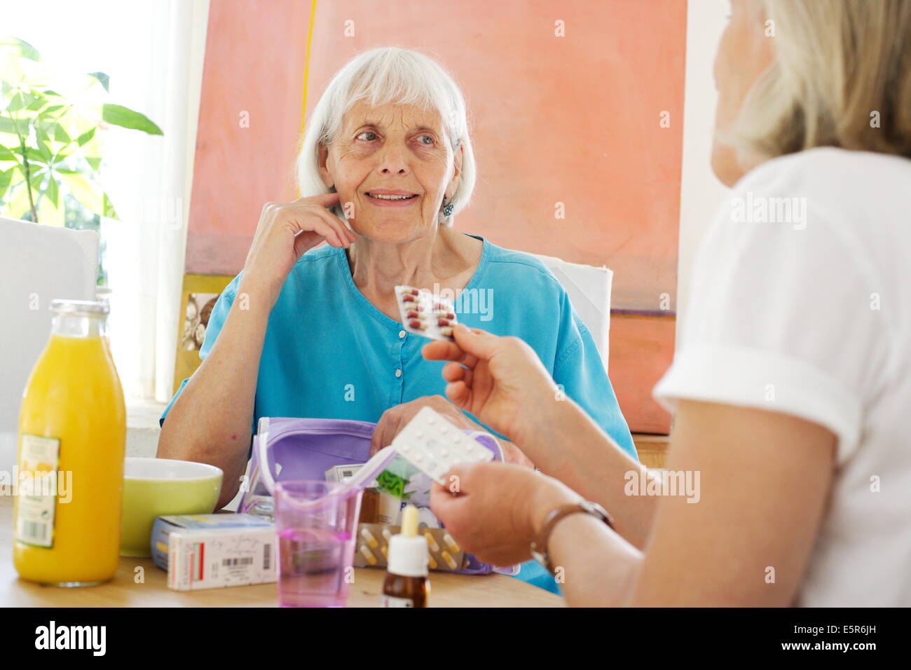 Woman assisting 80 year old woman taking medication Stock Photo - Alamy