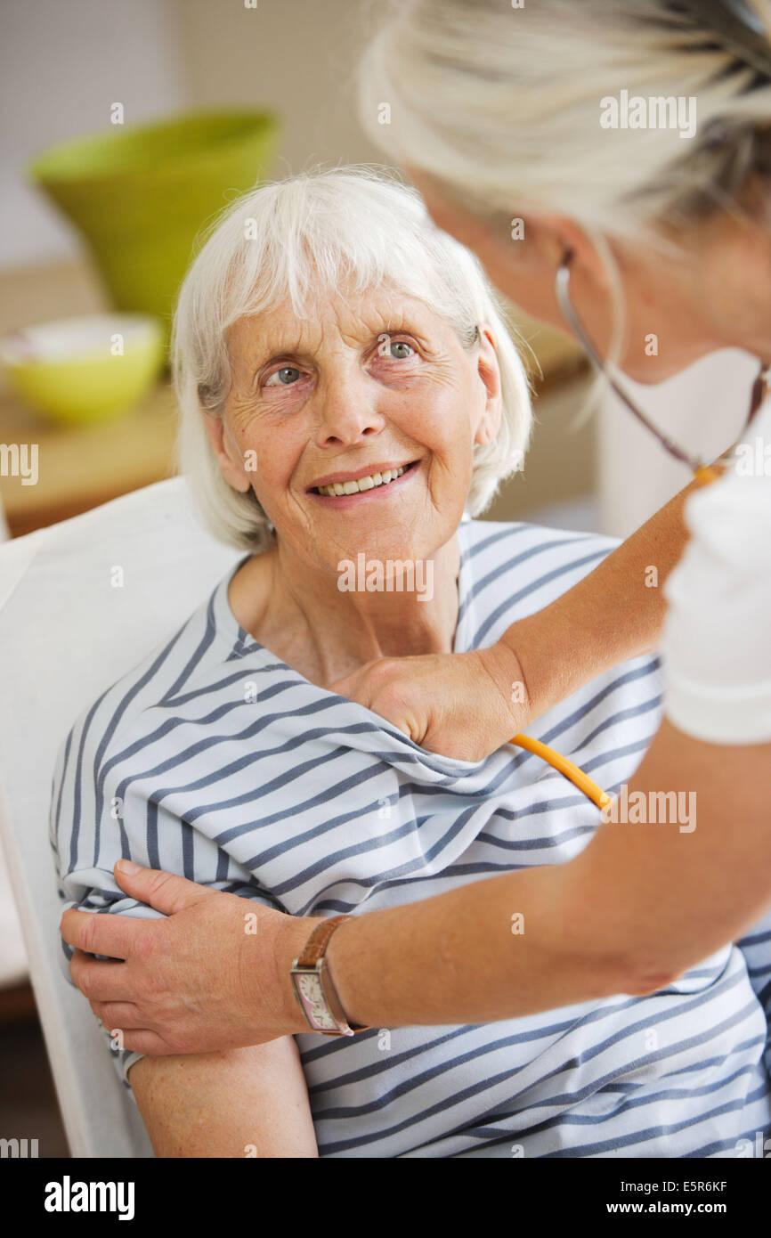 General practitioner examining 80 year old patient during home visit ...