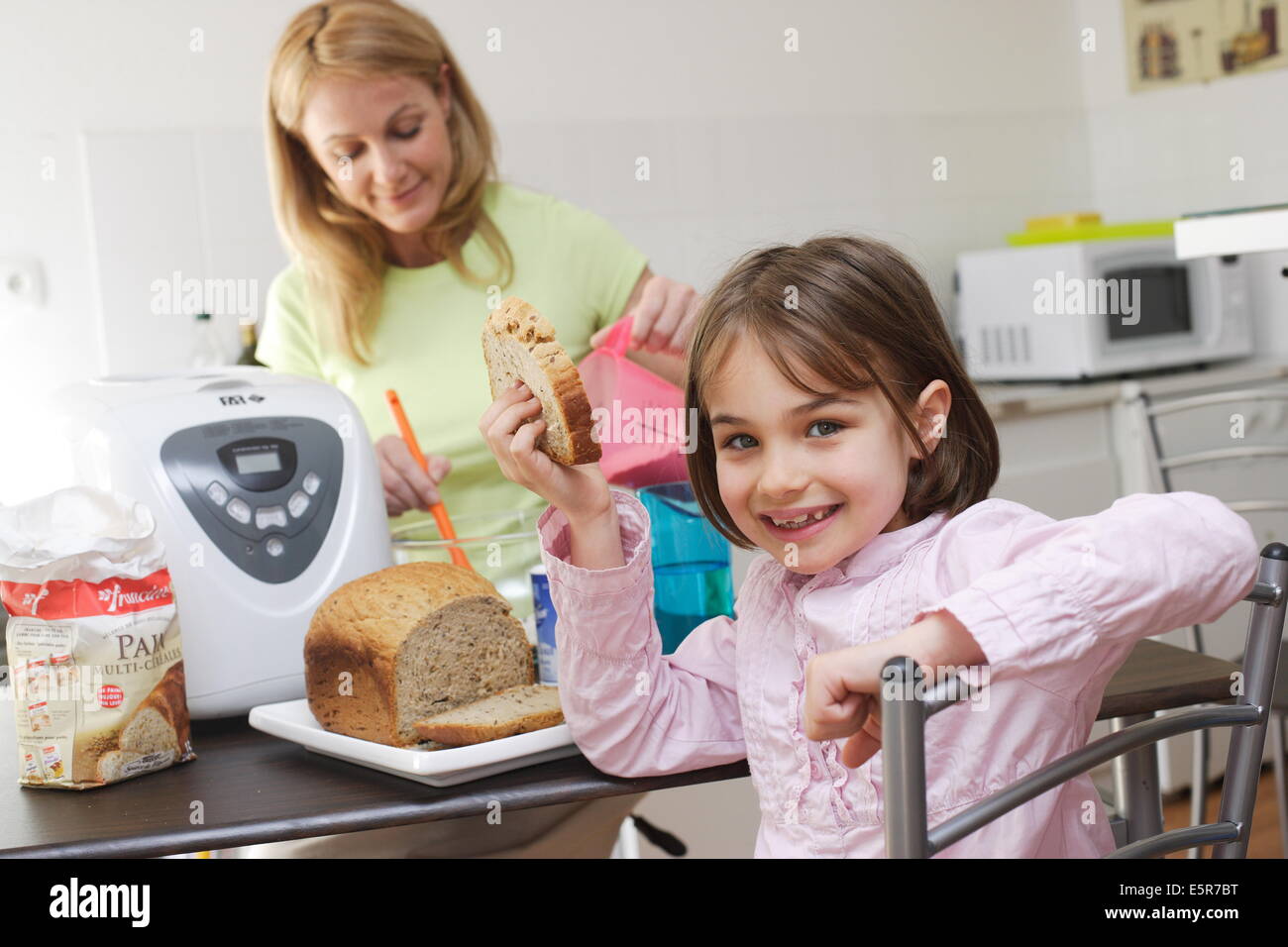Woman making home made bread with her daughter, with a bread machine ...