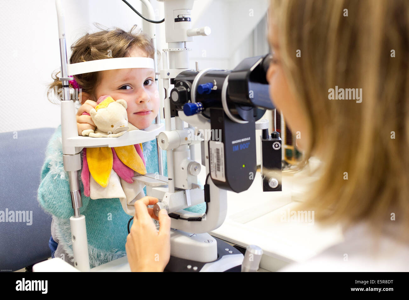 Ophthalmologist examining the interior of the eye of a young boy with ...