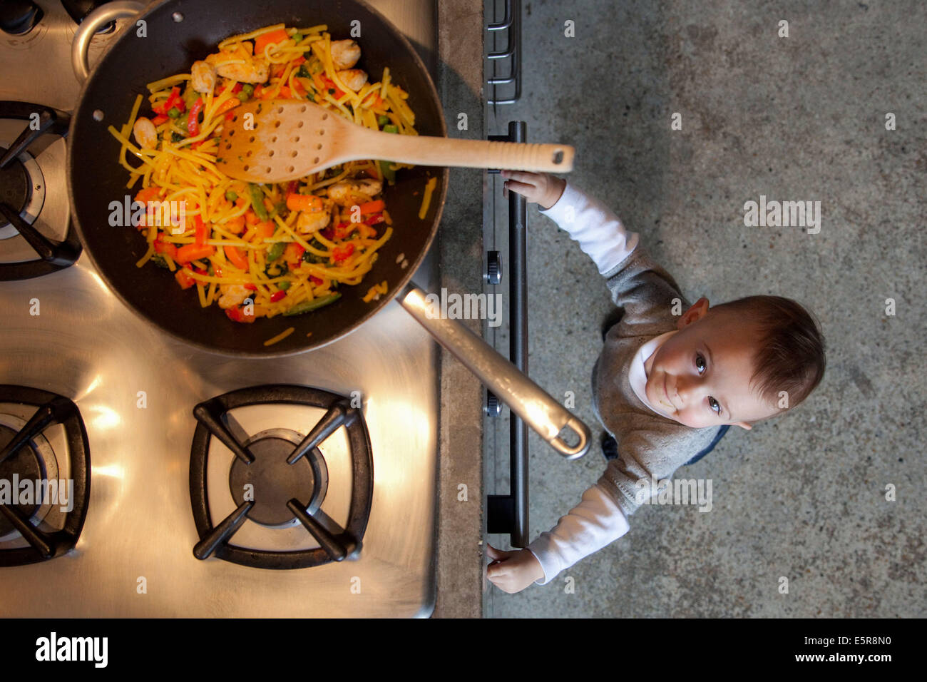 14 month old baby standing by a cooking stove Stock Photo - Alamy