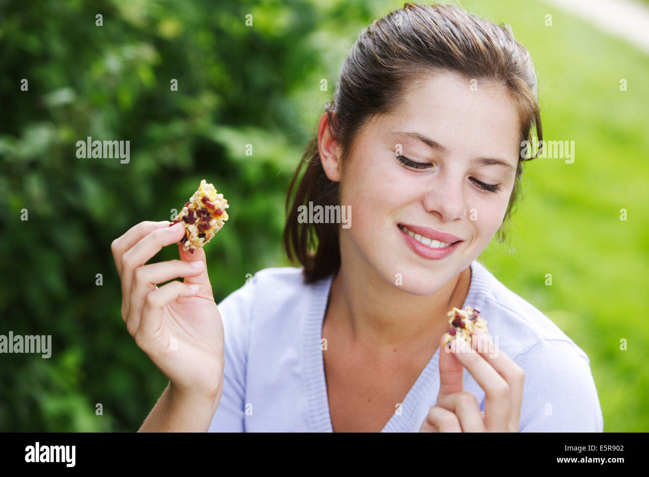 Teenage girl eating cereal bar Stock Photo - Alamy