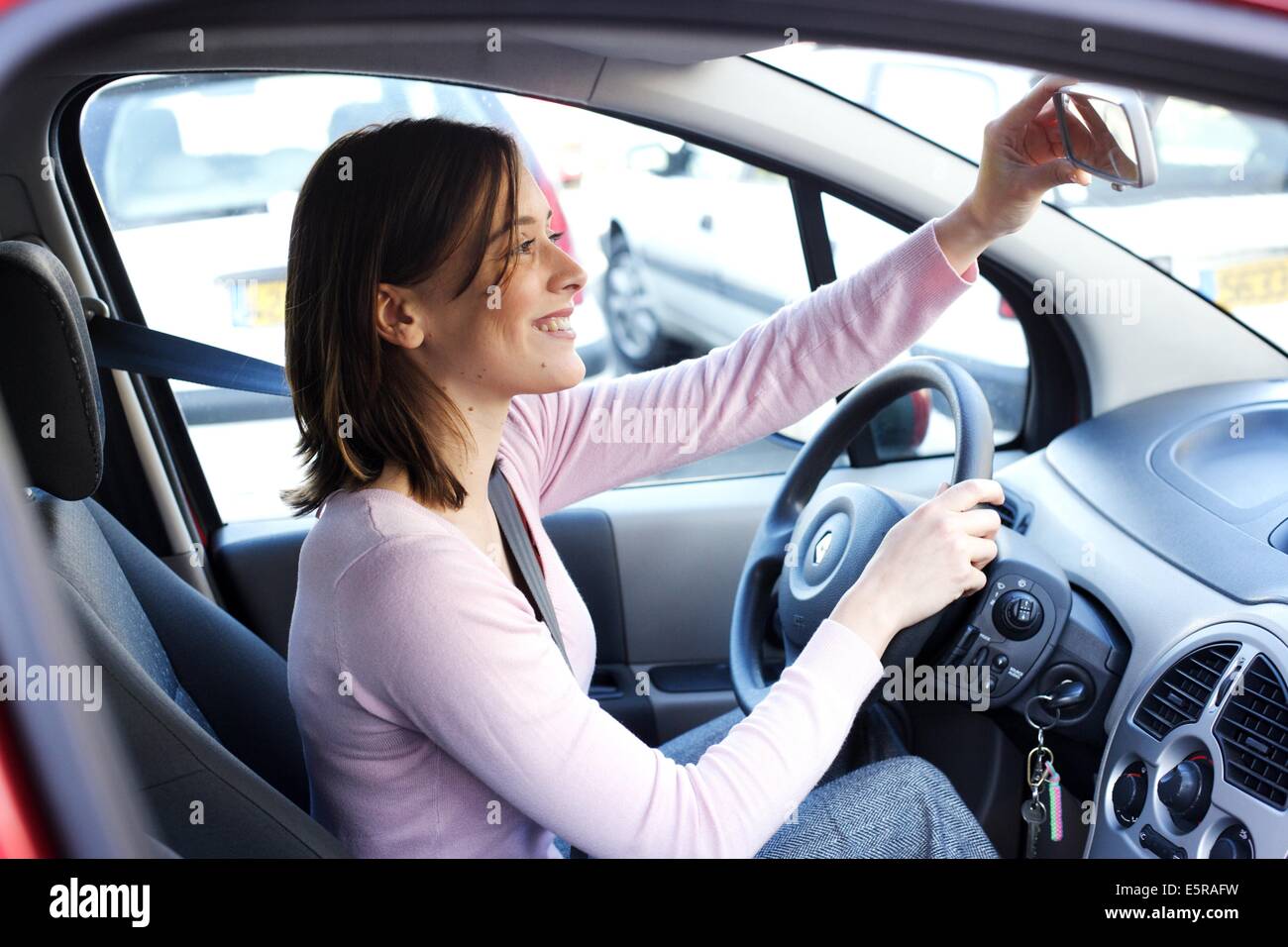 Woman adjusting rearview mirror Stock Photo - Alamy