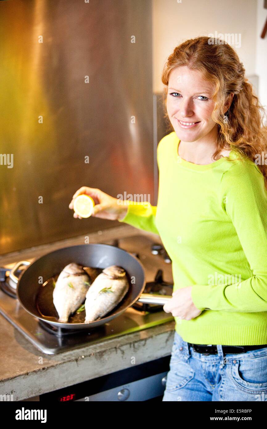 Woman cooking fish Stock Photo - Alamy