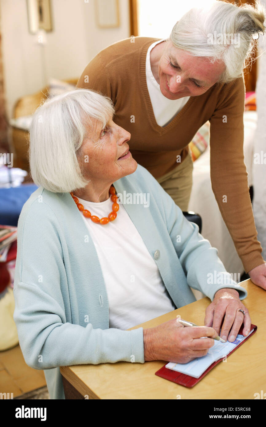 Woman helping elderly woman doing paperwork Stock Photo - Alamy