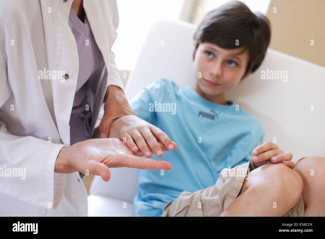 Doctor examining the hand of a 9 year-old boy Stock Photo - Alamy