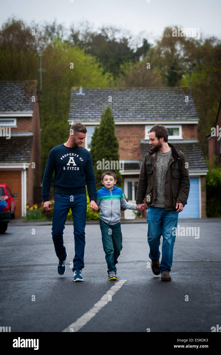 2 male parents walking down the street with boy of 8 9 10 Stock Photo ...