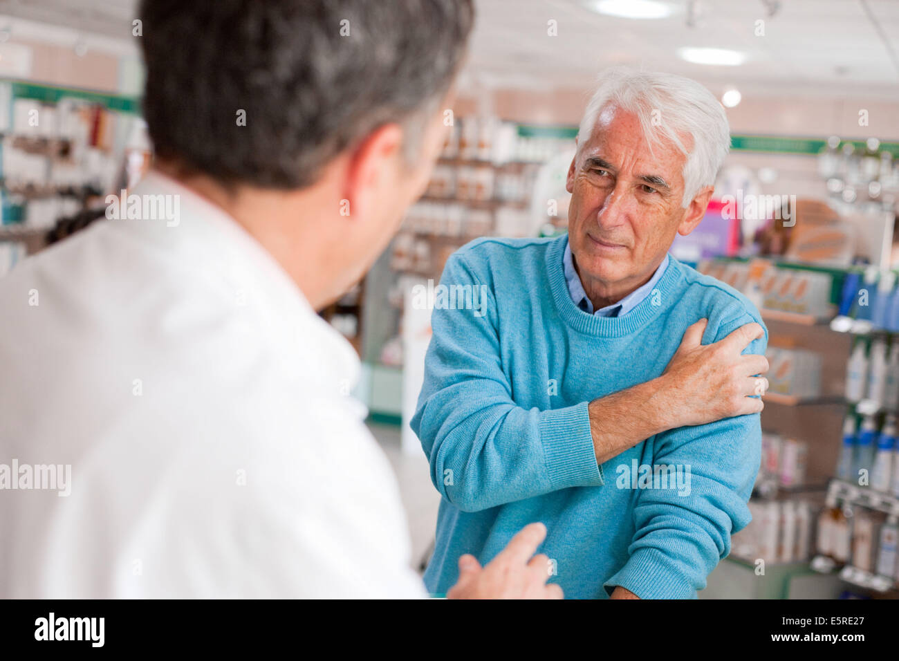 Pharmacist and customer suffering from shoulder pain Stock Photo - Alamy
