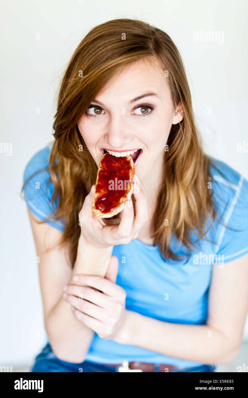 Woman eating a jam toast Stock Photo - Alamy