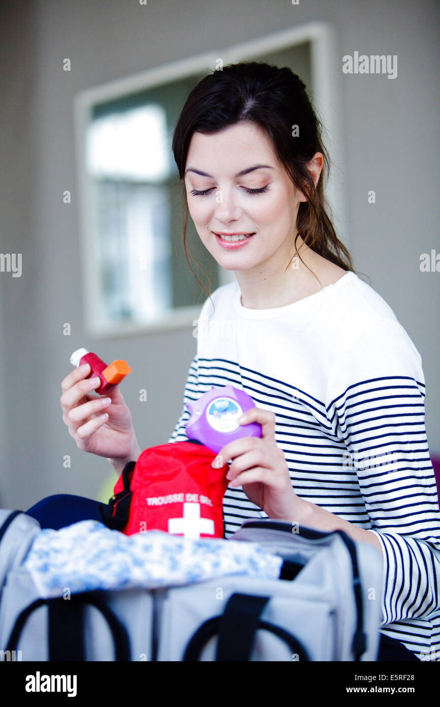 Woman preparing a first aid medical kit including asthma treatment ...