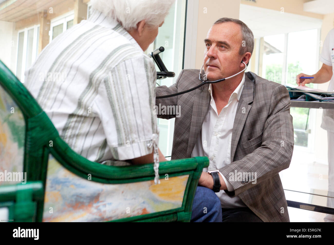 General practitioner talking with an elderly person during a visit in a ...