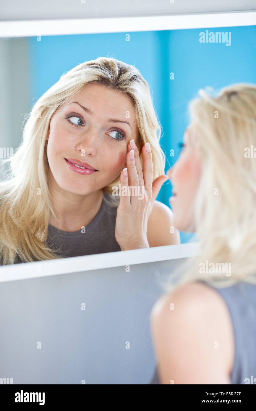 Woman checking her face in the mirror Stock Photo - Alamy