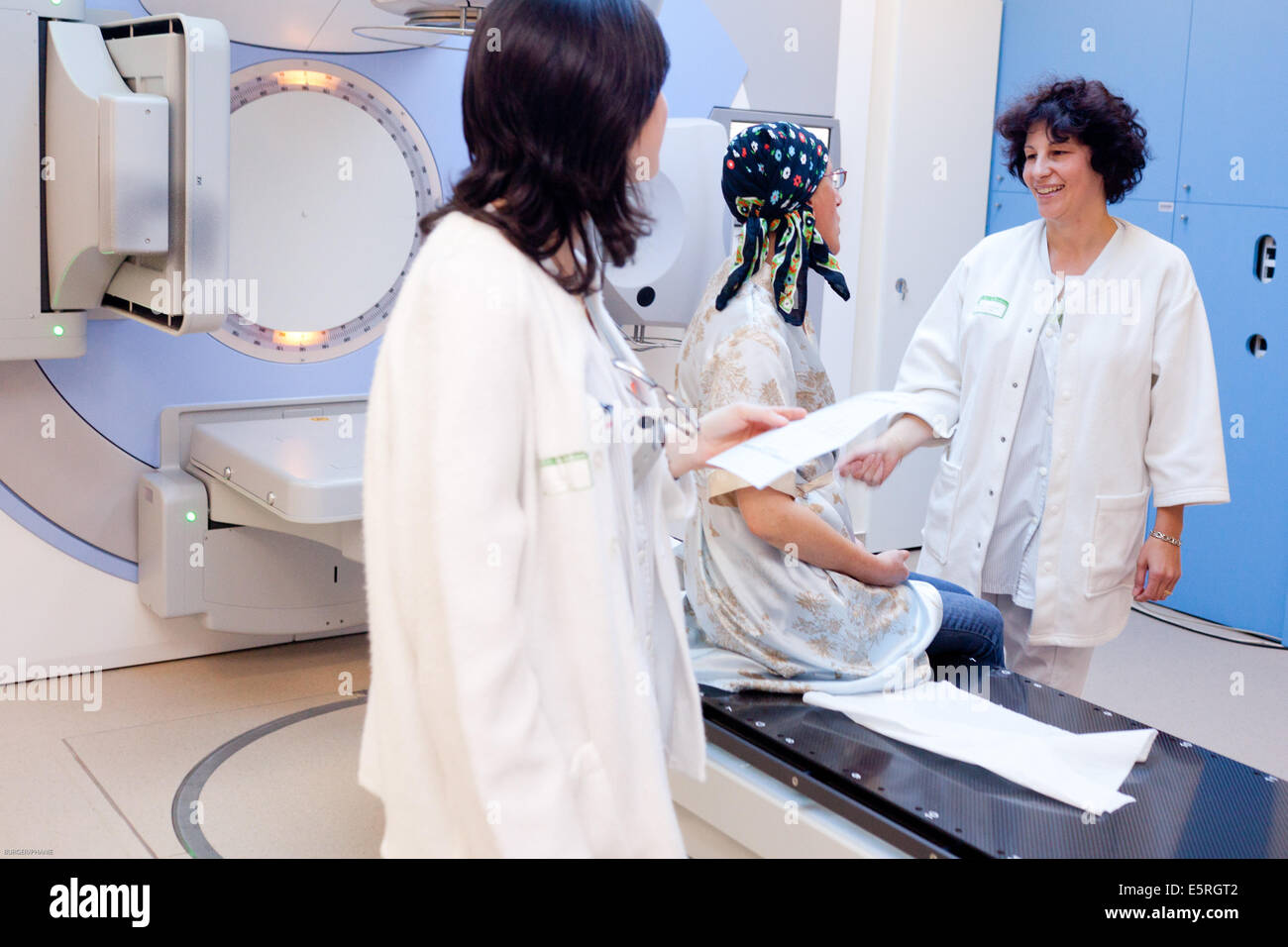 Radiotherapy radiographers talking to a female patient treated with ...