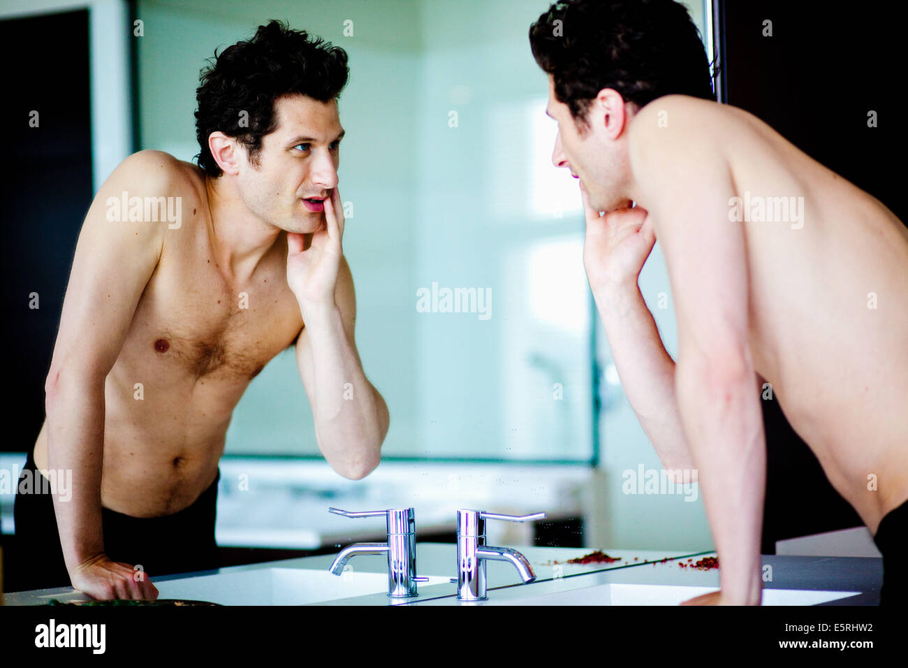 Man checking her face in the mirror Stock Photo - Alamy