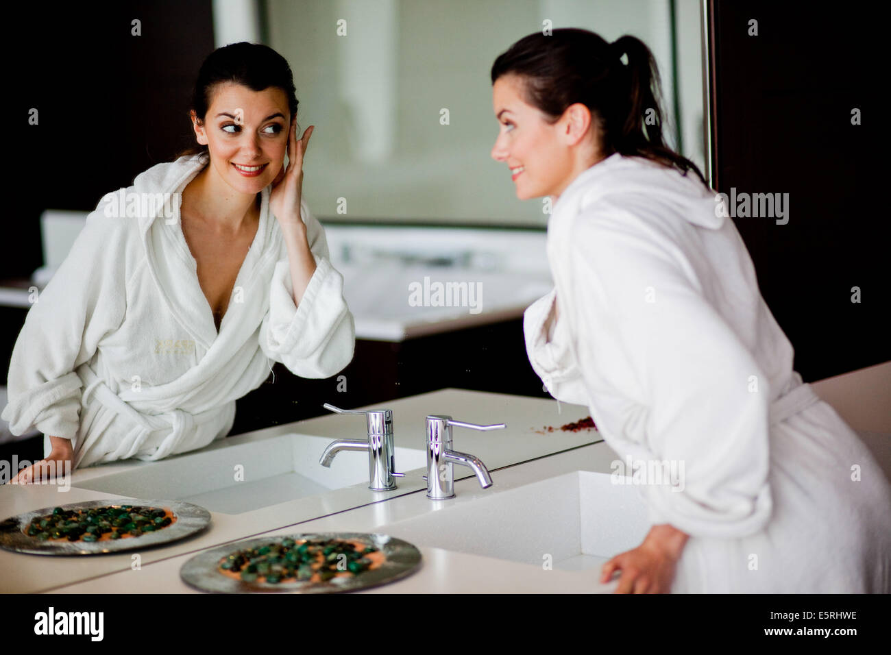 Woman checking her face in the mirror Stock Photo - Alamy