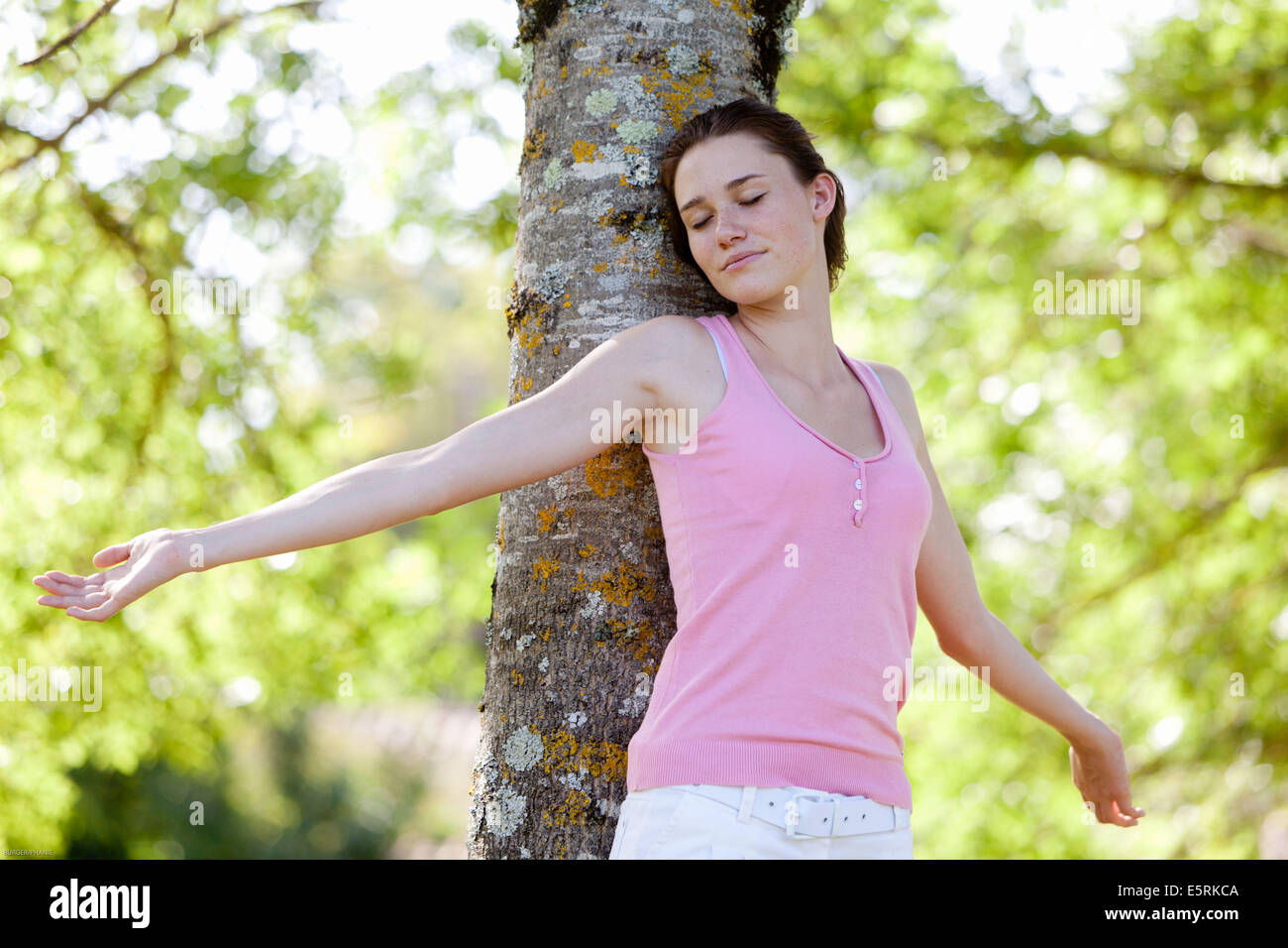 Woman leaning against a tree Stock Photo - Alamy