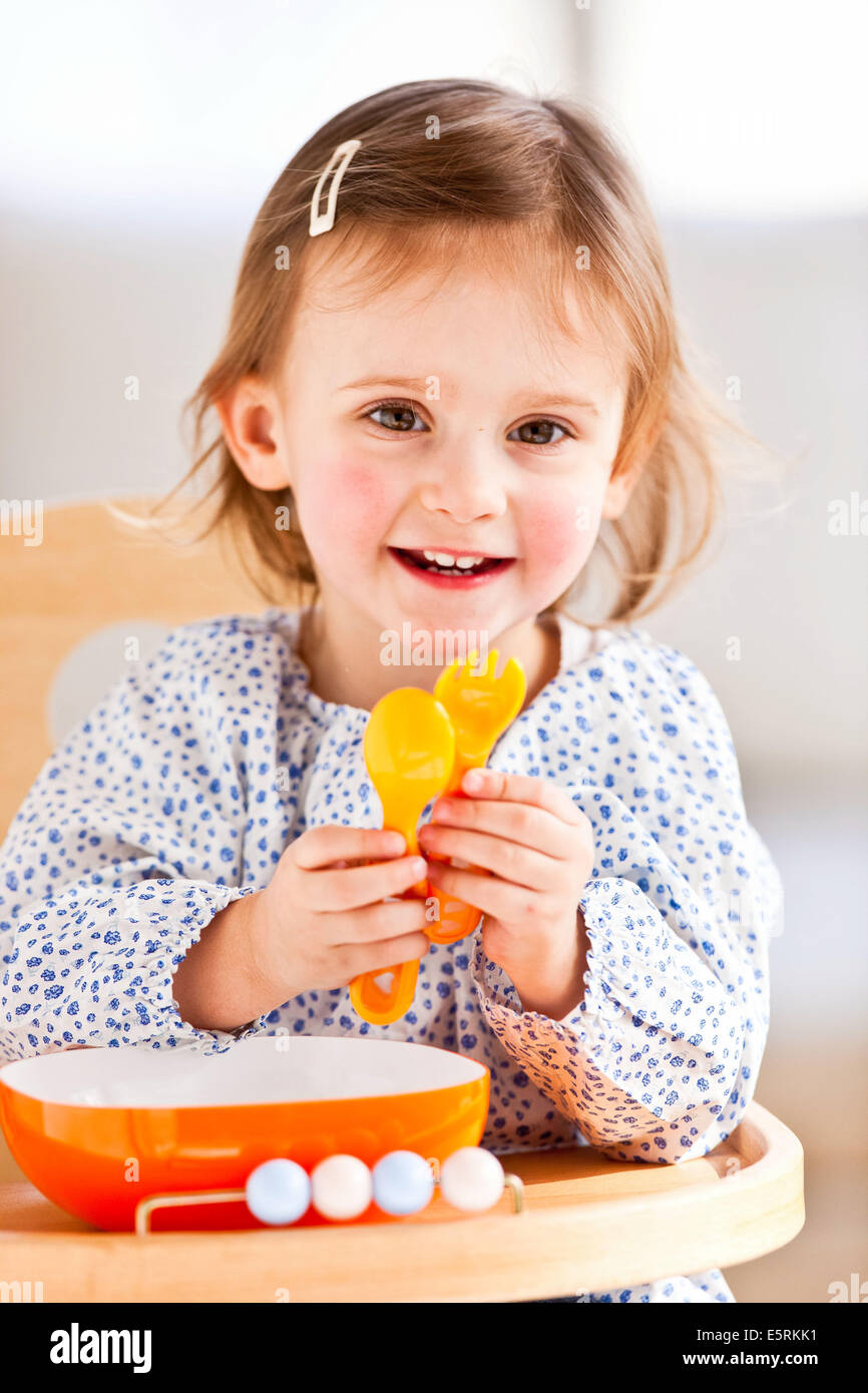 3-year-old girl holding plastic spoon and fork Stock Photo - Alamy