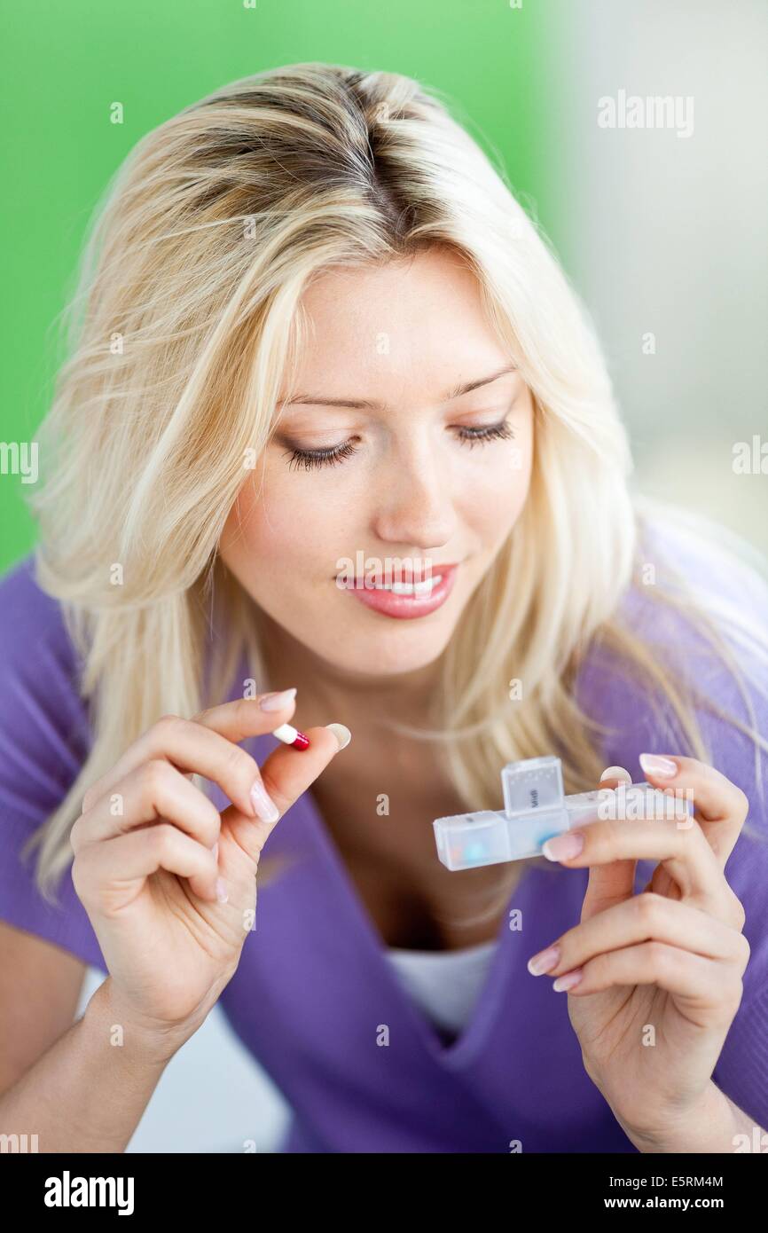 Woman taking medication from a pillbox Stock Photo - Alamy