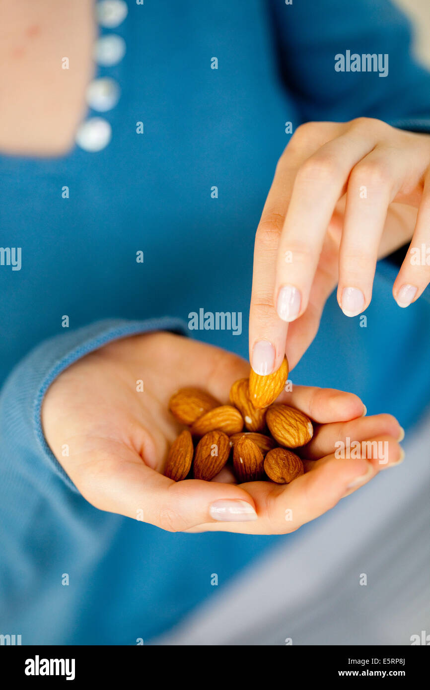 Woman eating almonds Stock Photo - Alamy