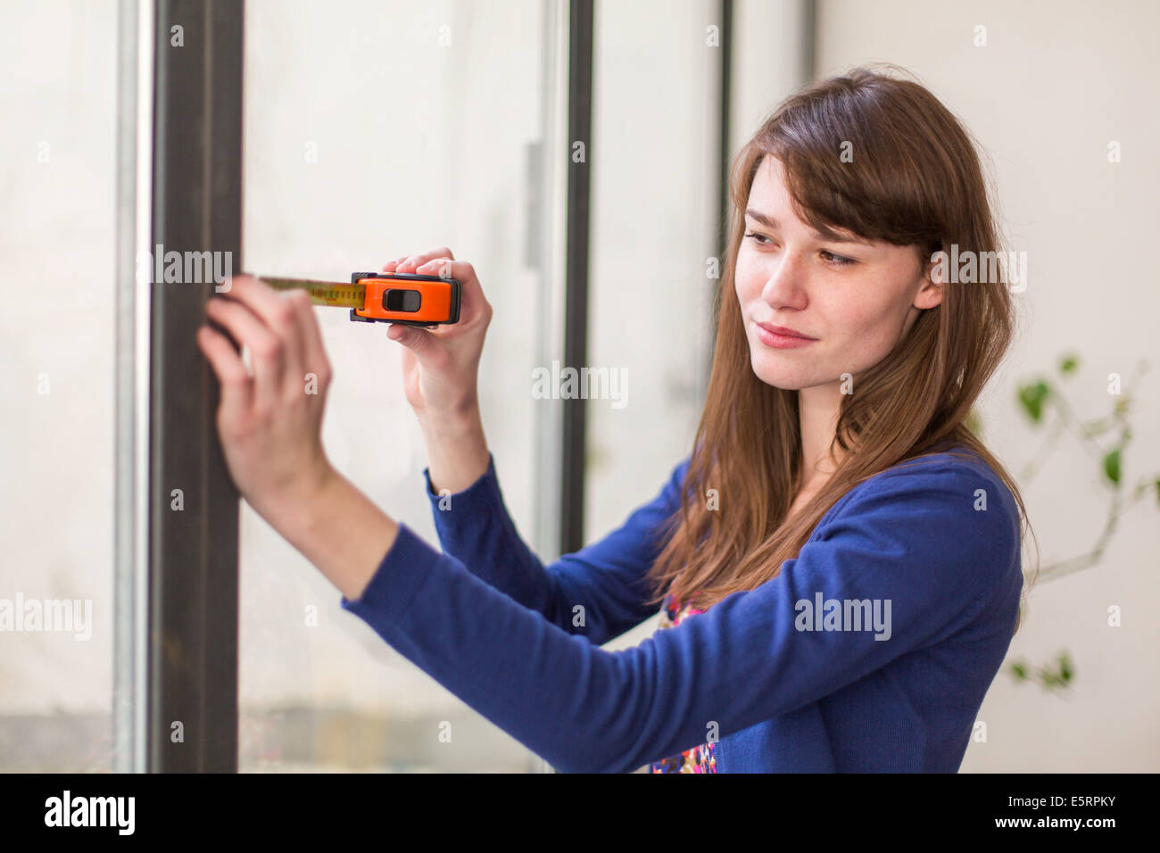 Do-it-yourself, Woman using tape measure Stock Photo - Alamy