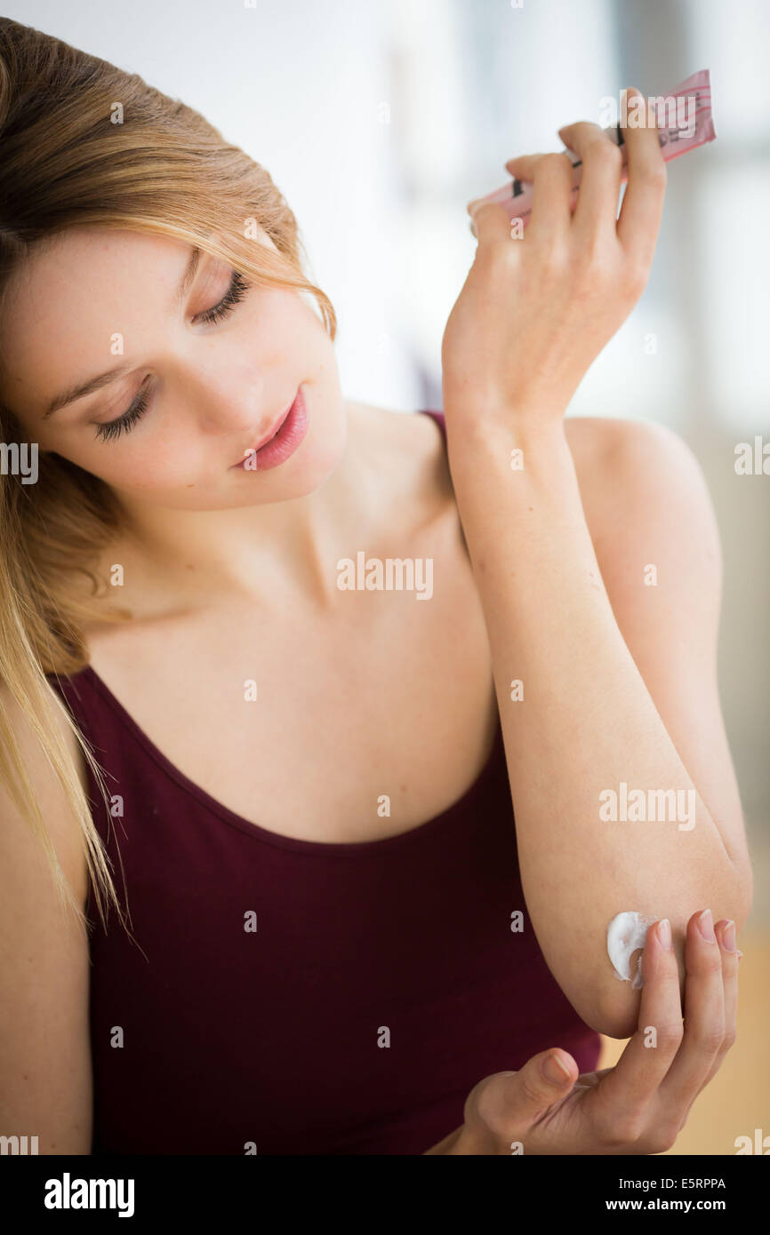 Woman applying pomade on her elbow Stock Photo - Alamy