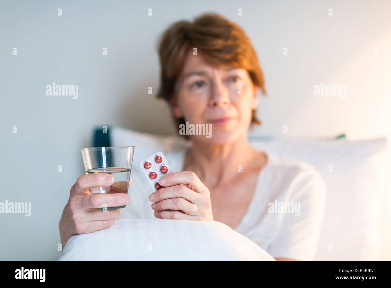 Restless woman taking tablets in bed unable to sleep Stock Photo - Alamy