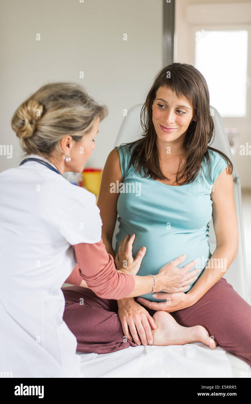 Gynecologist palpating the womb of a pregnant woman to estimate the ...