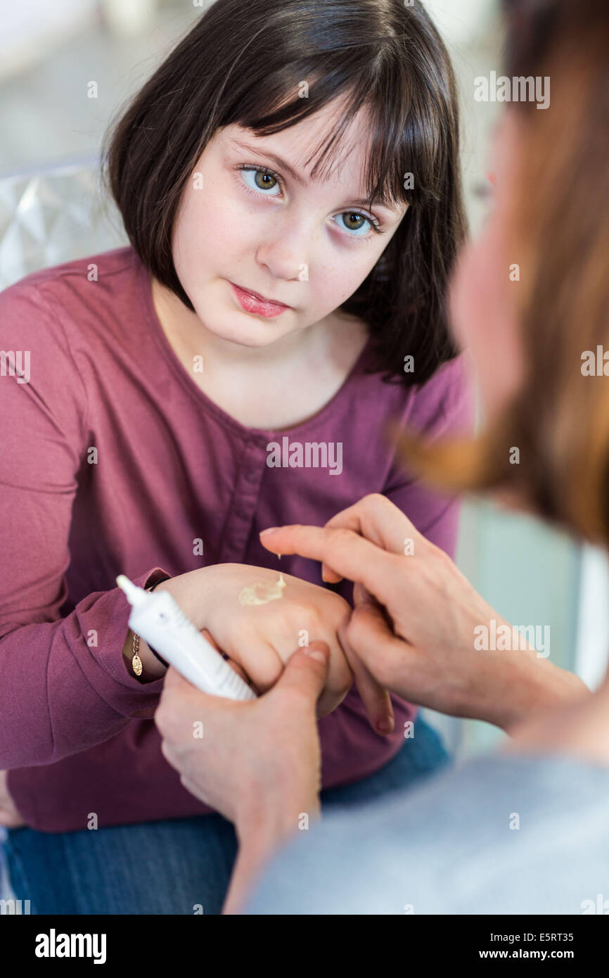 Mother applying pomade on her daughter's hand Stock Photo - Alamy