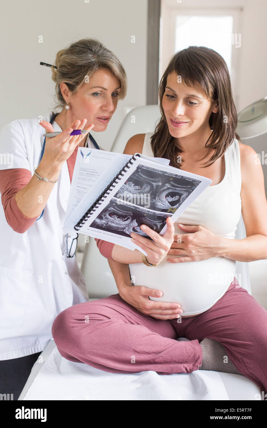 Gynecologist commenting foetal ultrasound scans of a pregnant woman ...