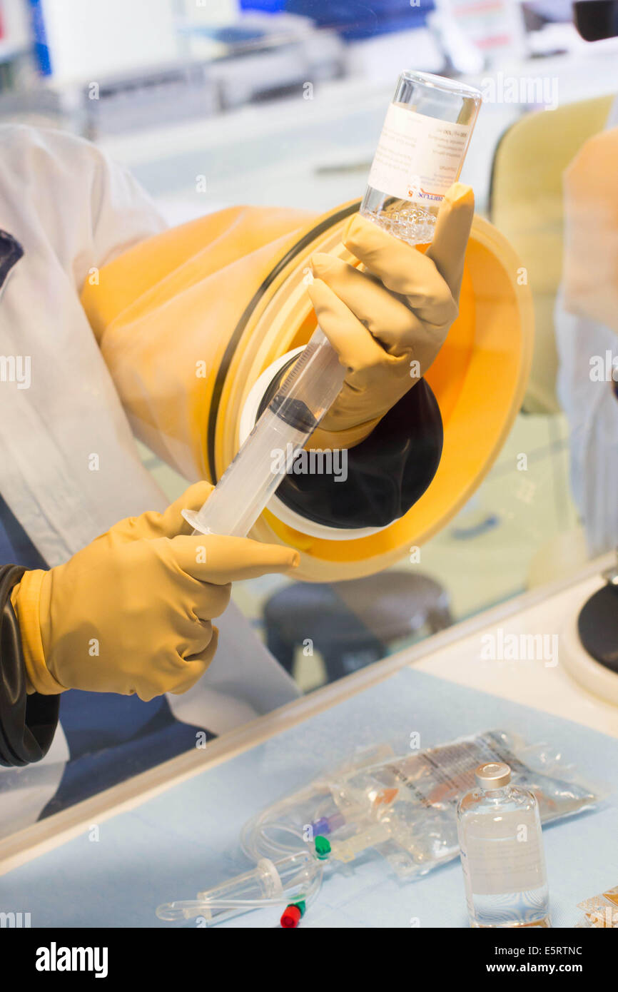 A compounder is preparing chemotherapy treatments under glove box ...