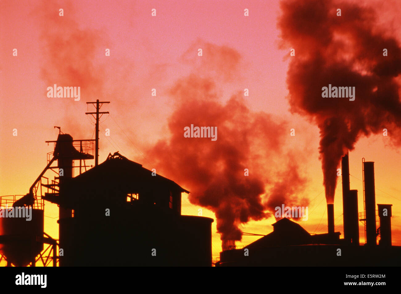 Silhouette of factory with chimneys emitting smoke, sunset Stock Photo ...