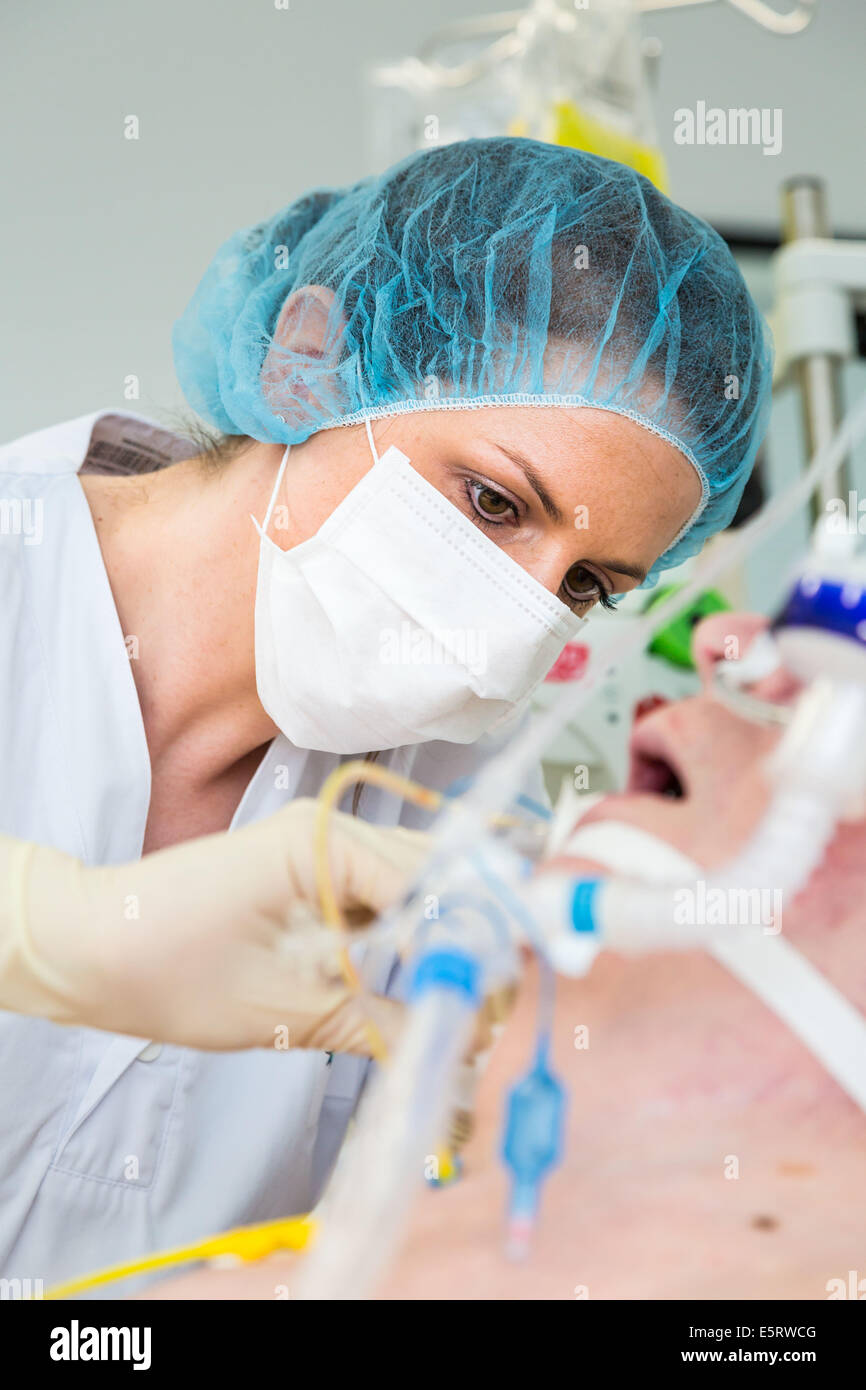 Nurse performing a treatment on a patient under respiratory assistance ...
