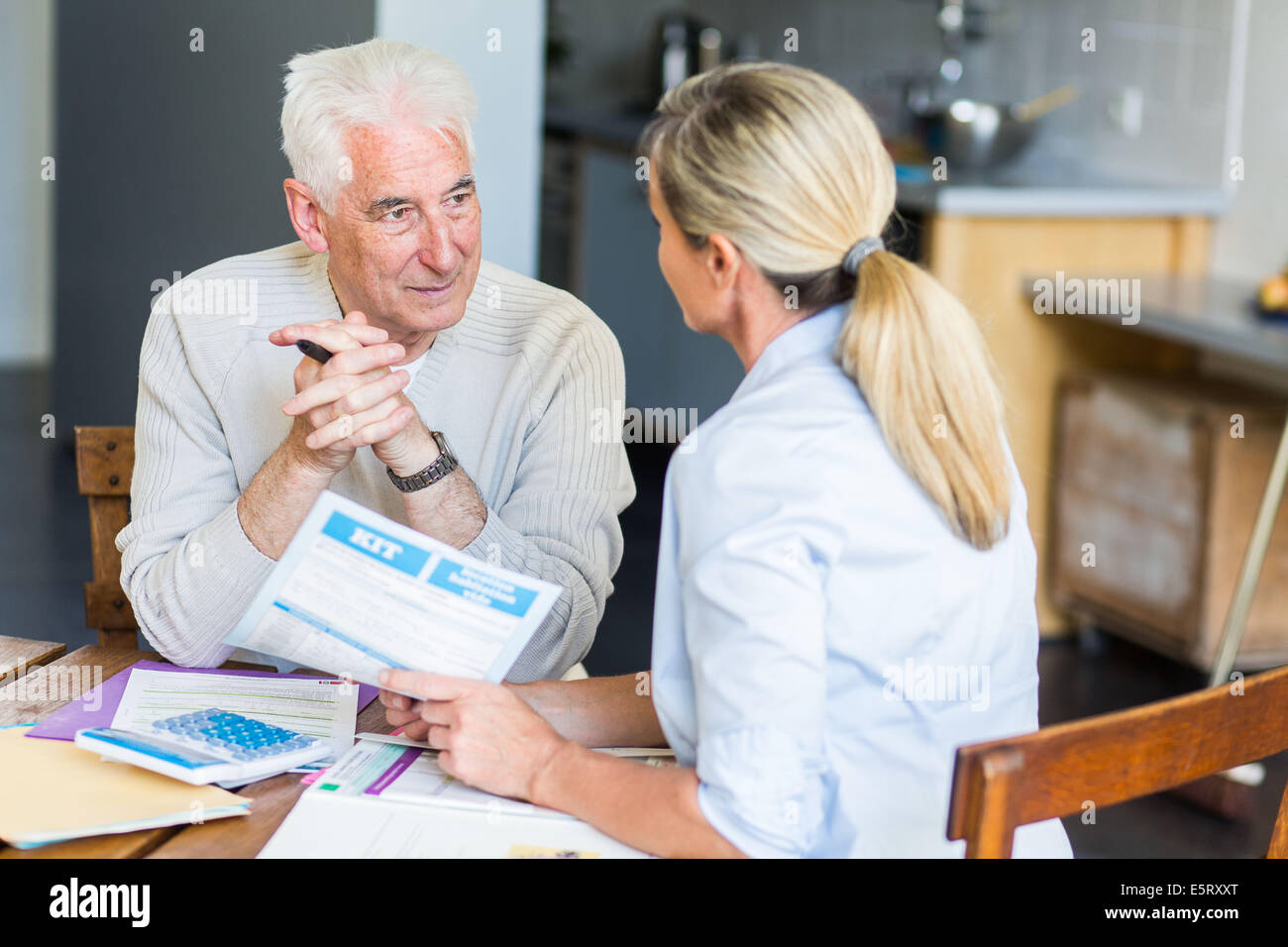 Woman helping elderly man doing paperwork Stock Photo - Alamy