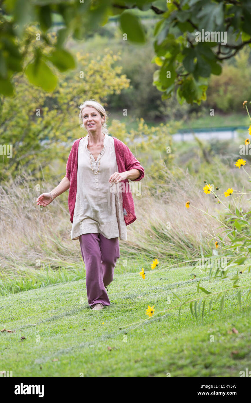 Woman walking through meadow Stock Photo - Alamy