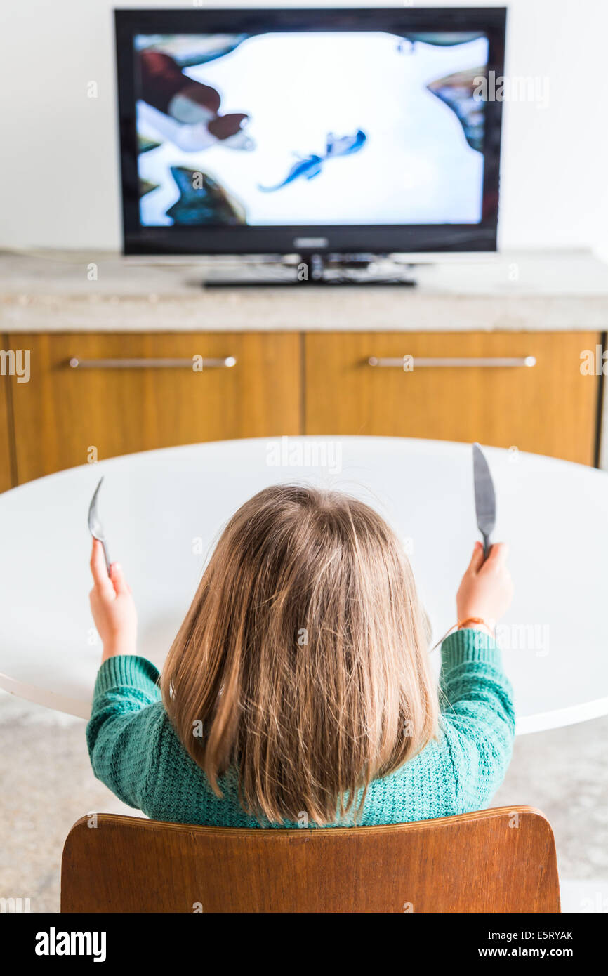 Girl watching TV while eating lunch Stock Photo - Alamy