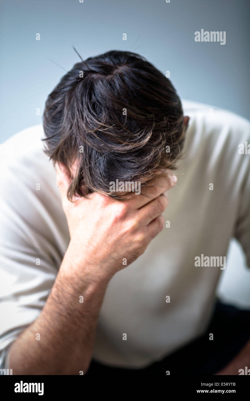 Depressed man holding his head in his hands Stock Photo - Alamy