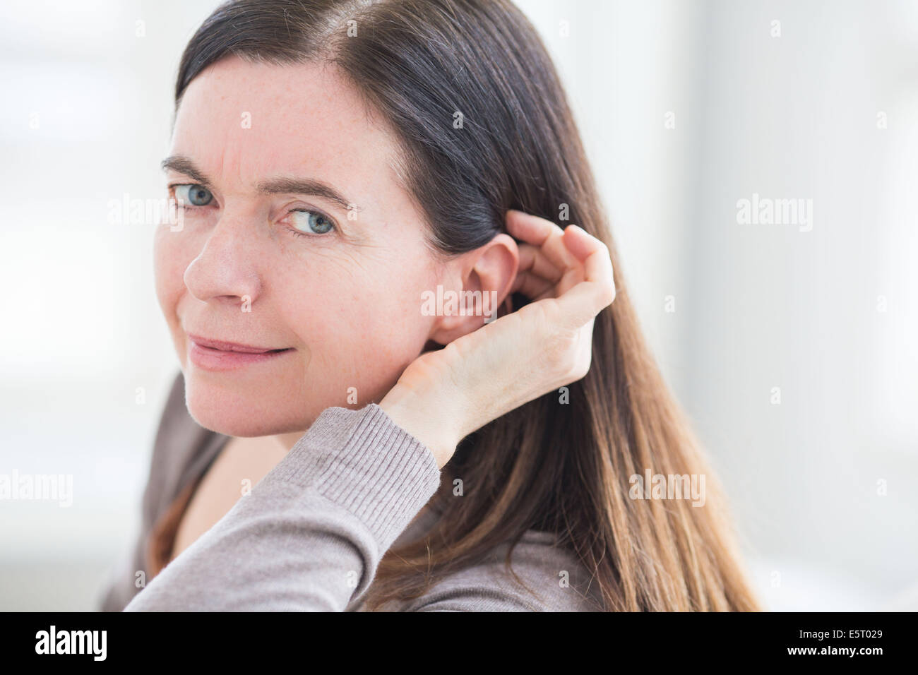Woman with her hand to her ear Stock Photo - Alamy