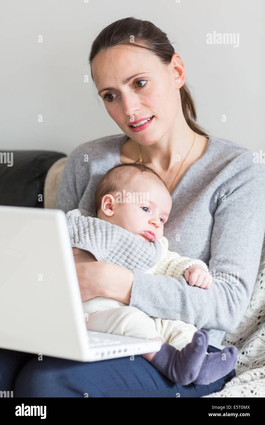 Woman using laptop computer with her 3 month old baby boy Stock Photo ...
