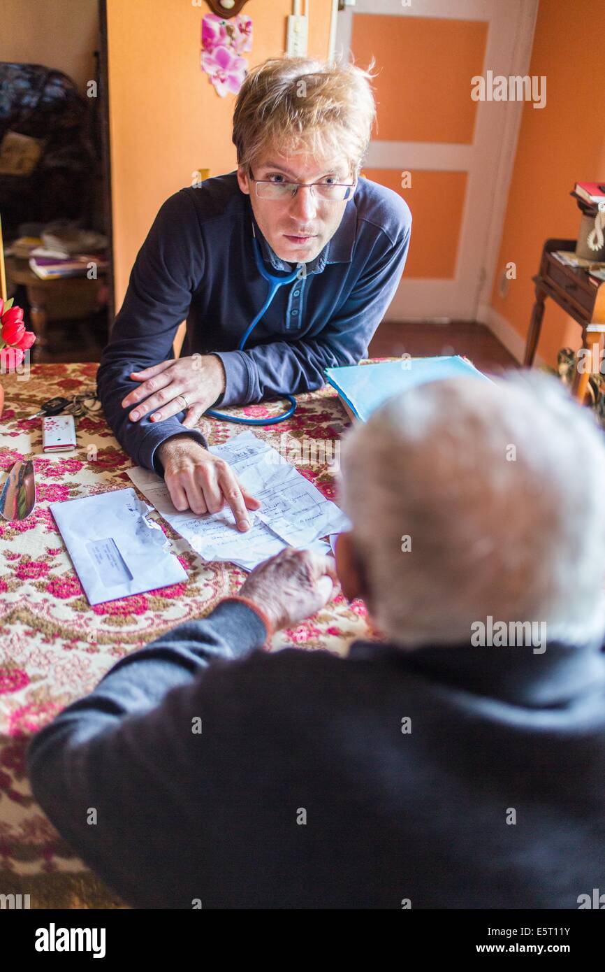 General practitioner on a home visit, talking to a patient affected by ...