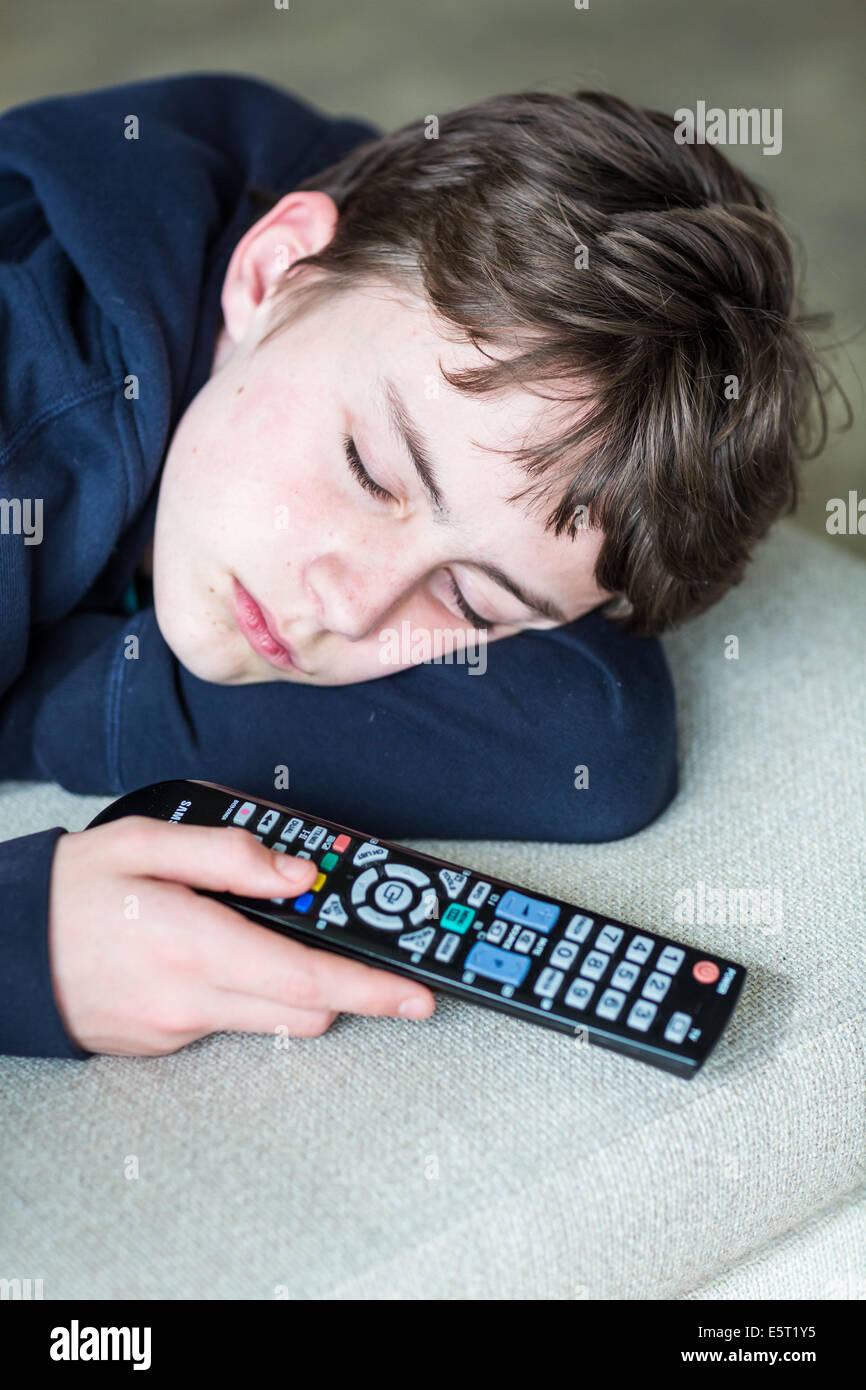 Teenage boy sleeping on a couch, holding a remote control Stock Photo ...