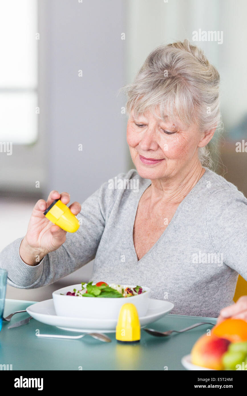 Woman adding salt on a salad Stock Photo - Alamy