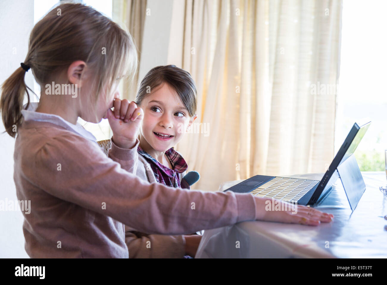 Sisters using laptop computer Stock Photo - Alamy