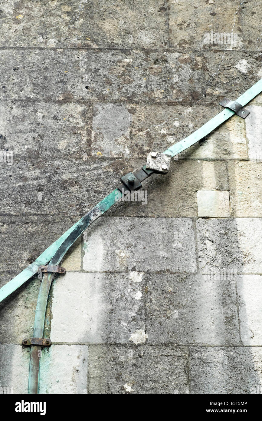 Section of flat copper lightening conductor on stone wall of UK church ...