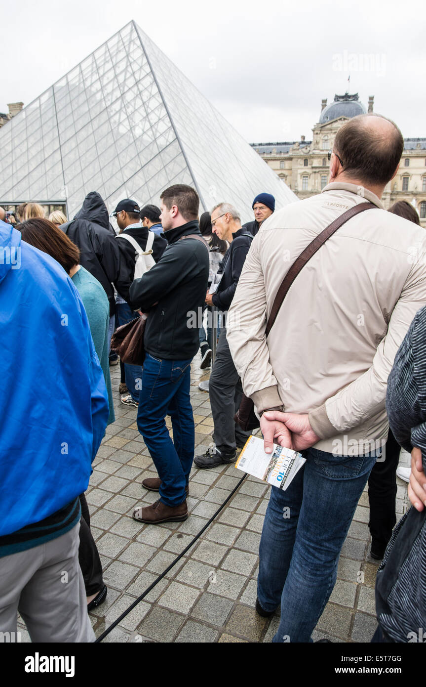 Visitors and tourists queue at the glass pyramid, entrance to the ...